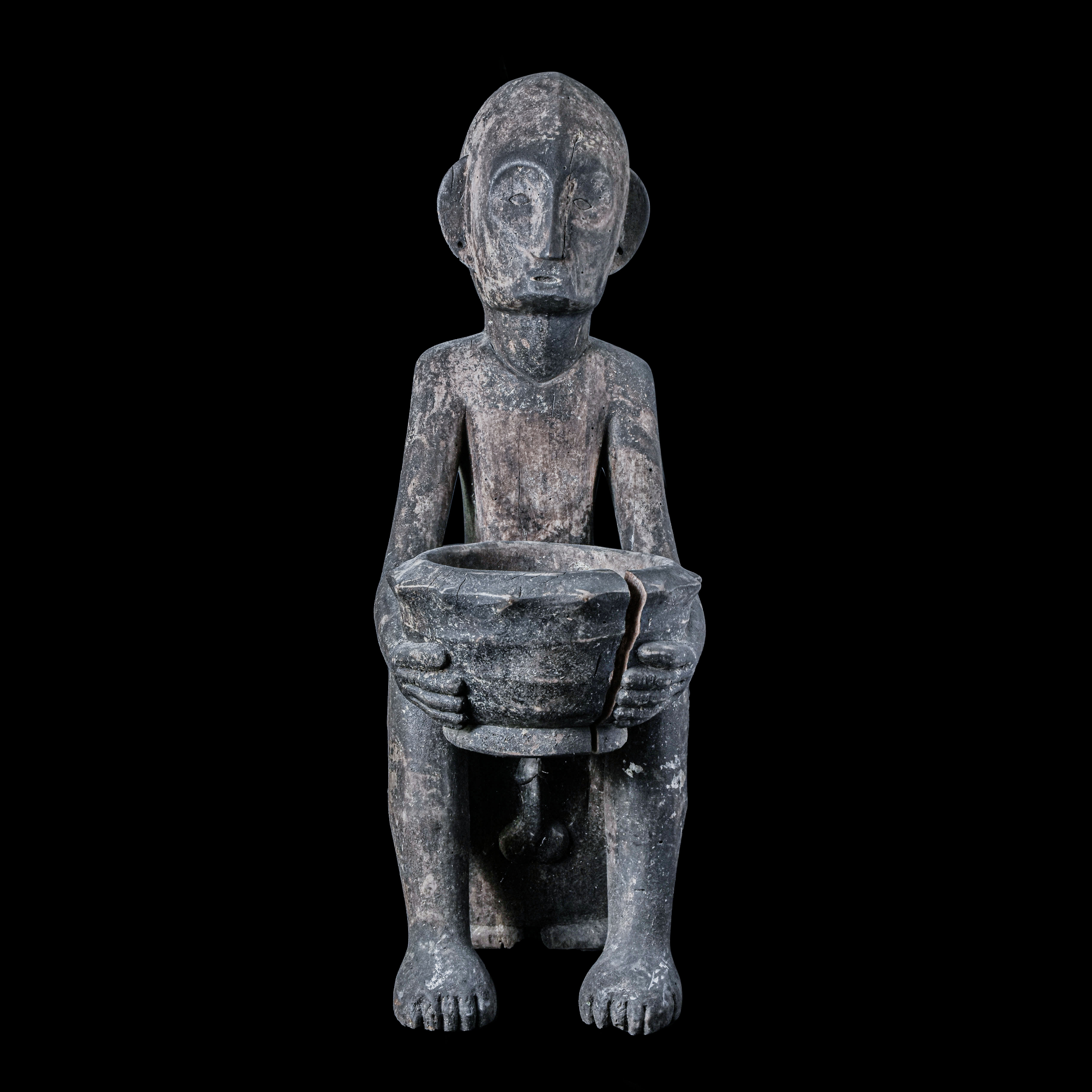 - A seated male figure holding bowl